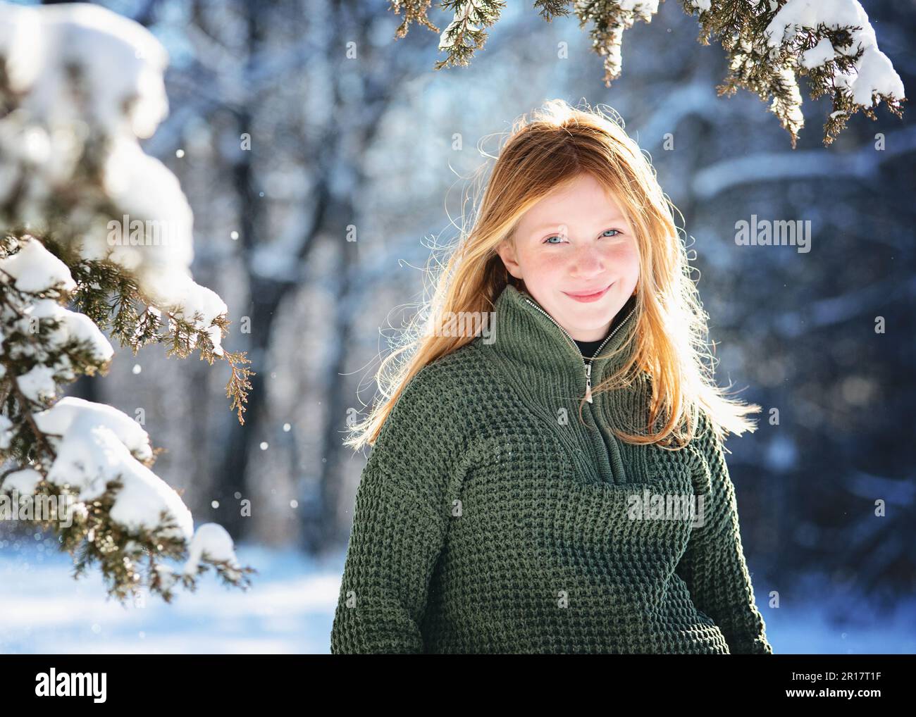 Happy tween girl with red hair in green sweater in the snow Stock Photo ...