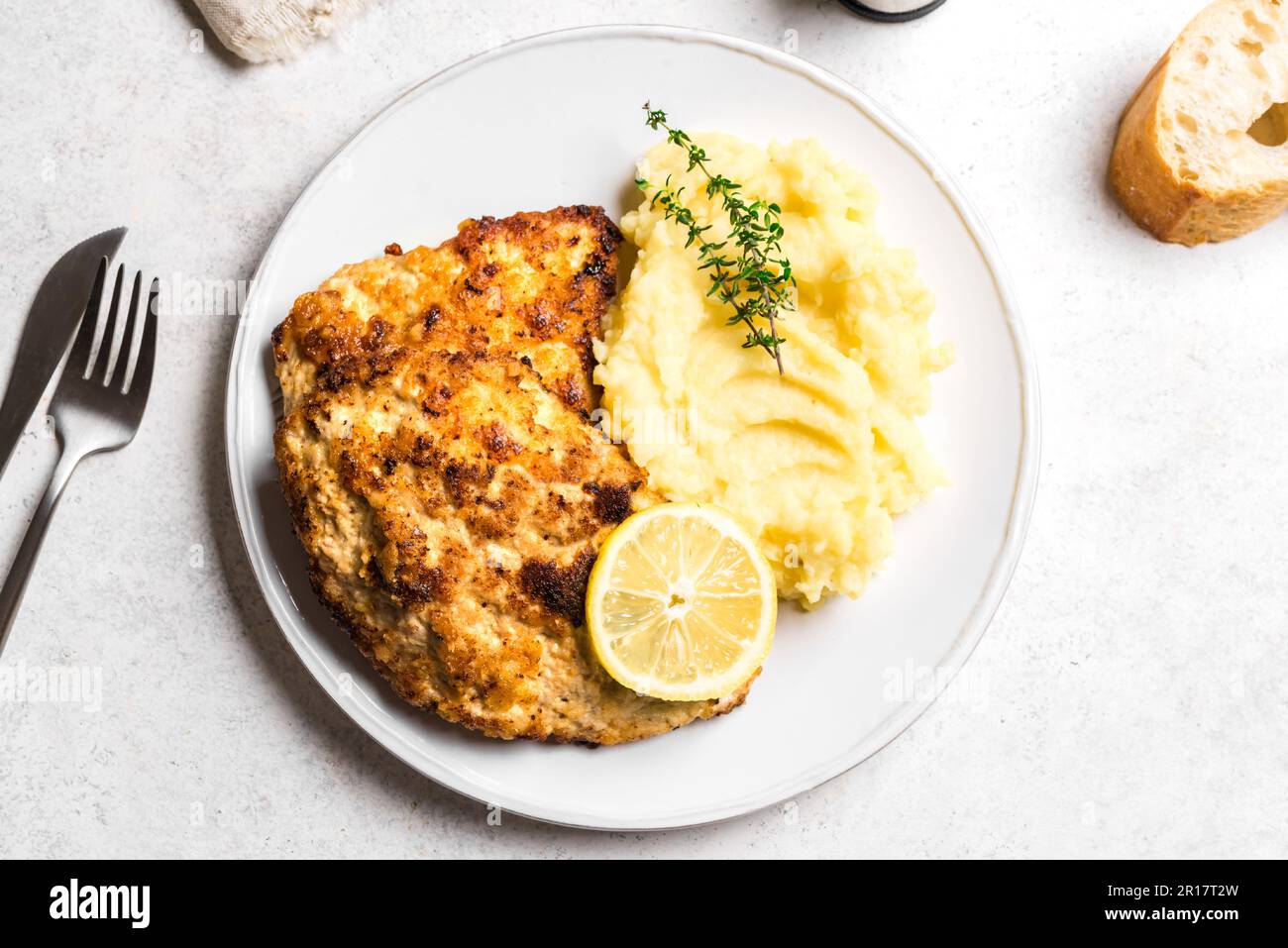 German schnitzel with fresh mashed potatoes, lemon and thyme close up ...