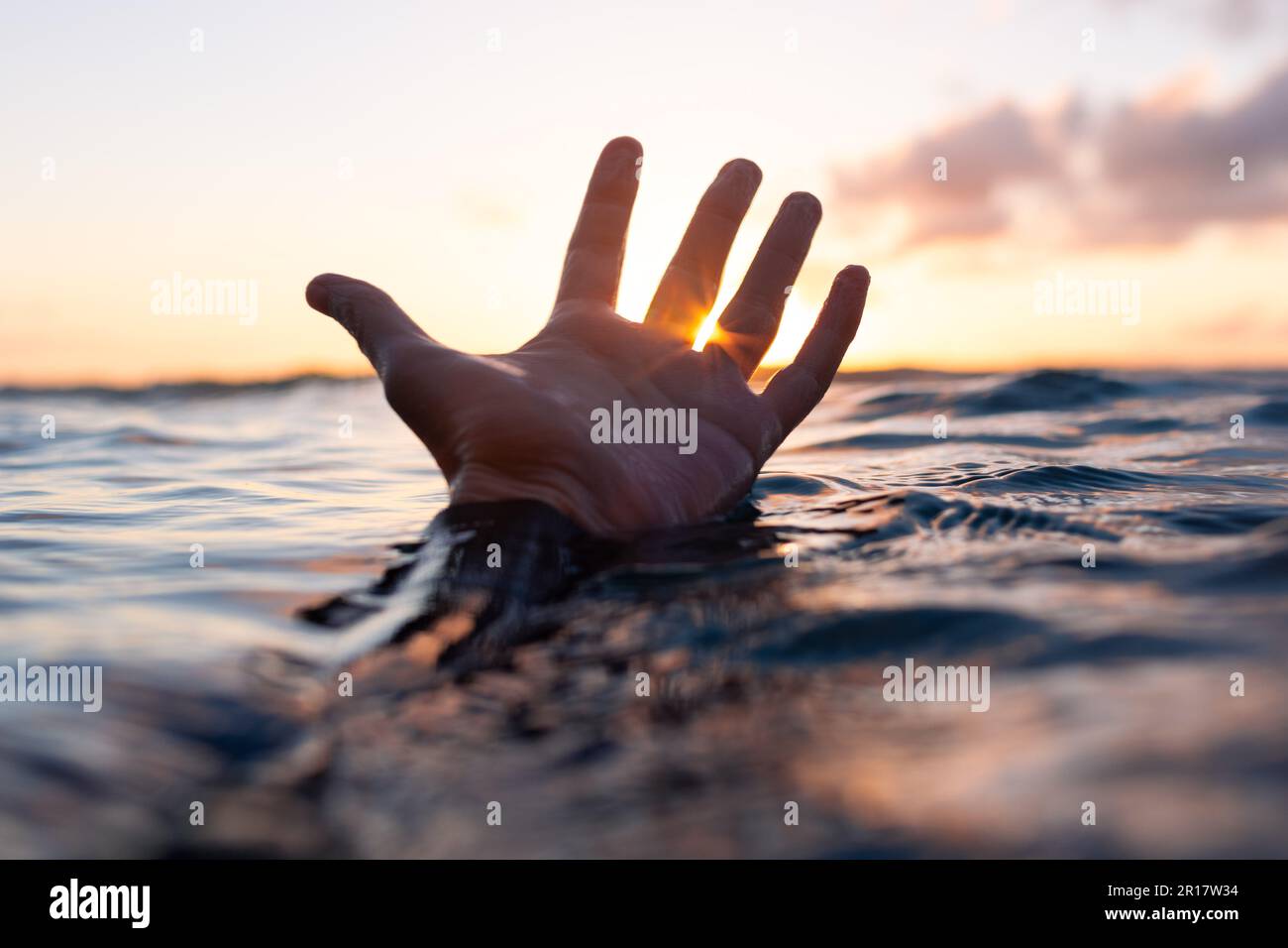 First person view of a hand floating in the ocean at sunset Stock Photo ...