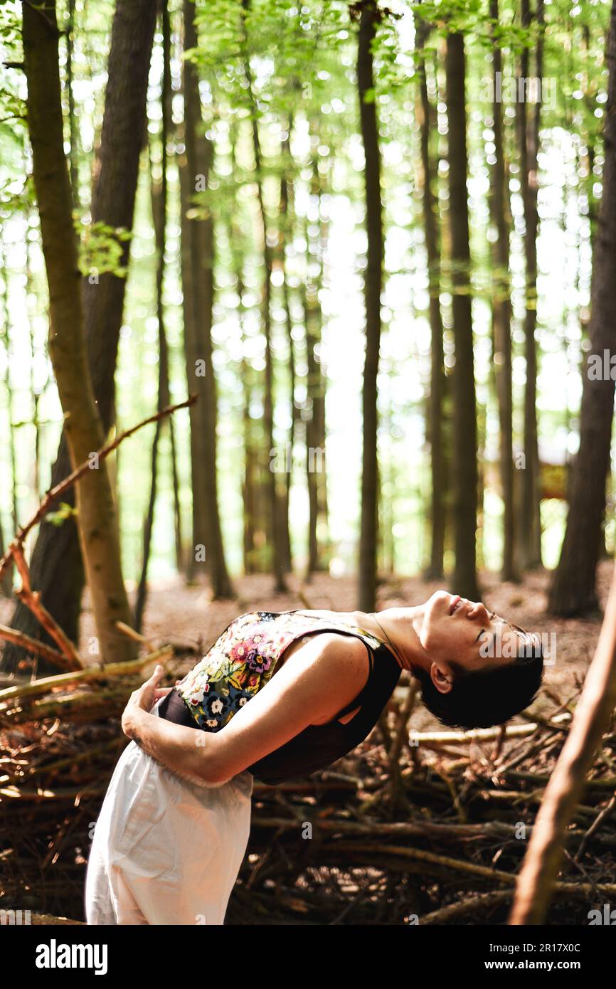 dancer arches back in sunlight feeling blissful in natural forrest ...