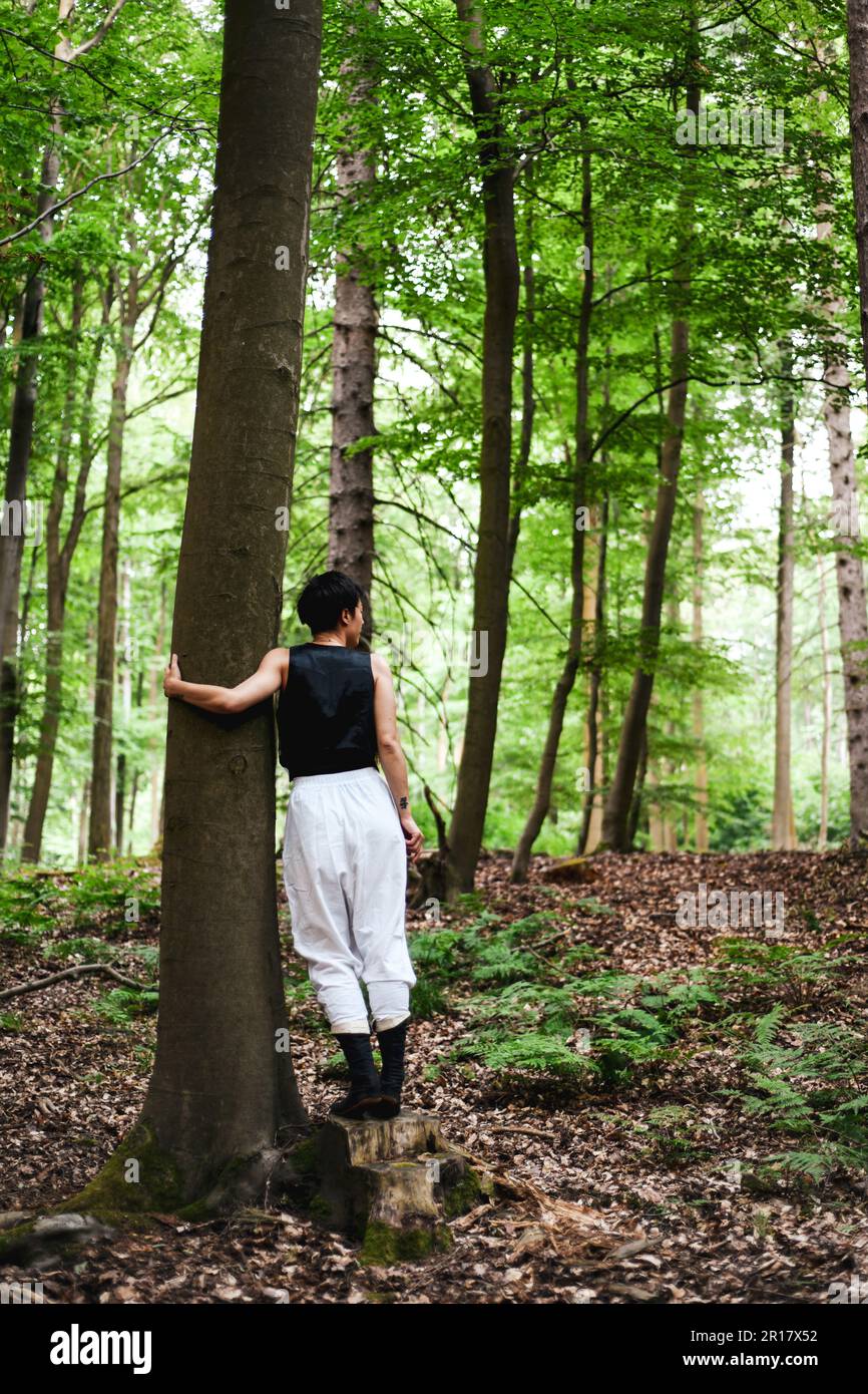Woman stands holding onto tree in middle of green fresh forrest Stock ...