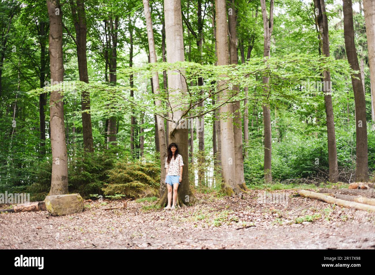 girl stands under beautiful green tree branch by forrest in Europe ...