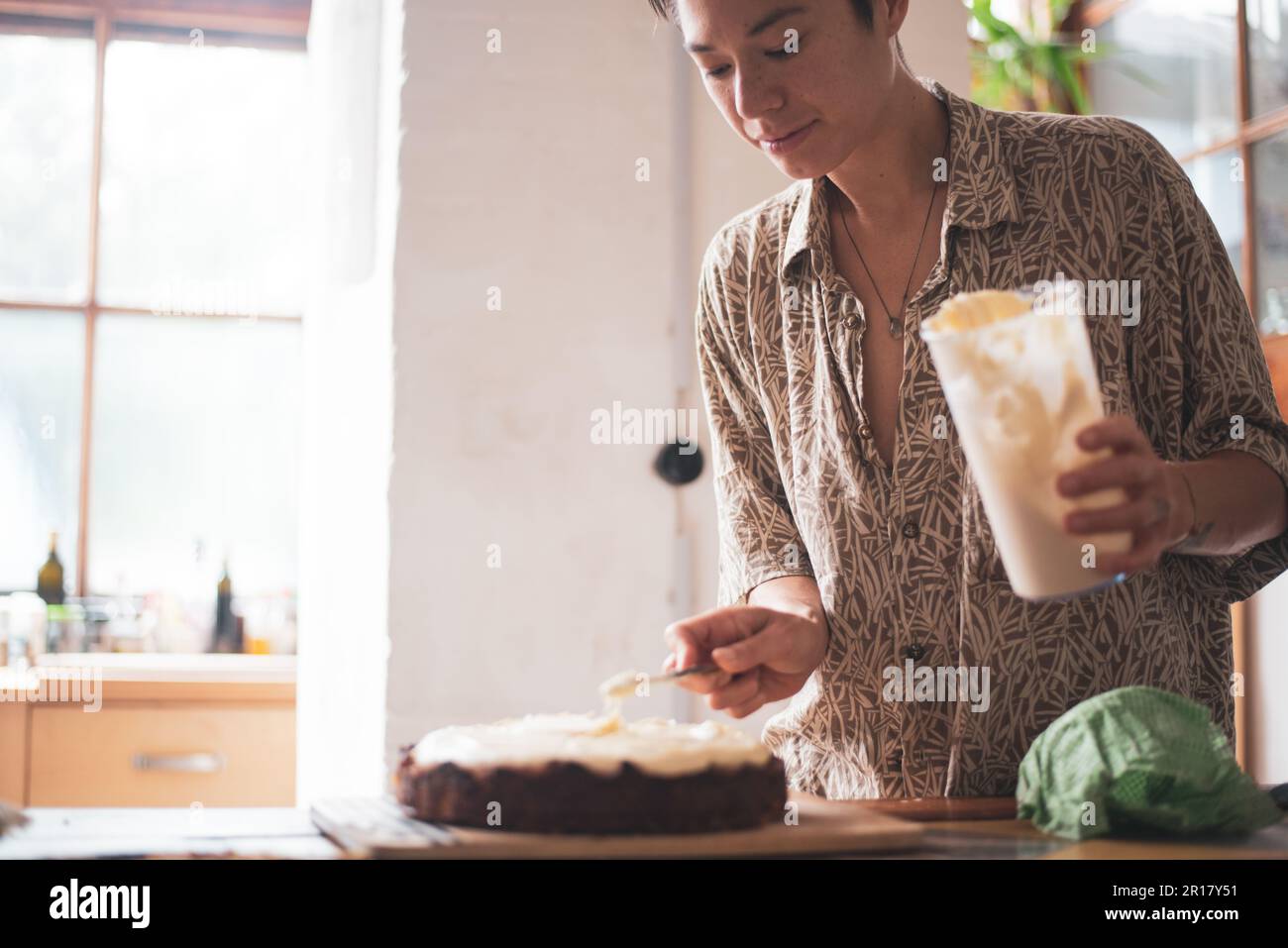 Asian person icing birthday cake at home by window in germany Stock ...