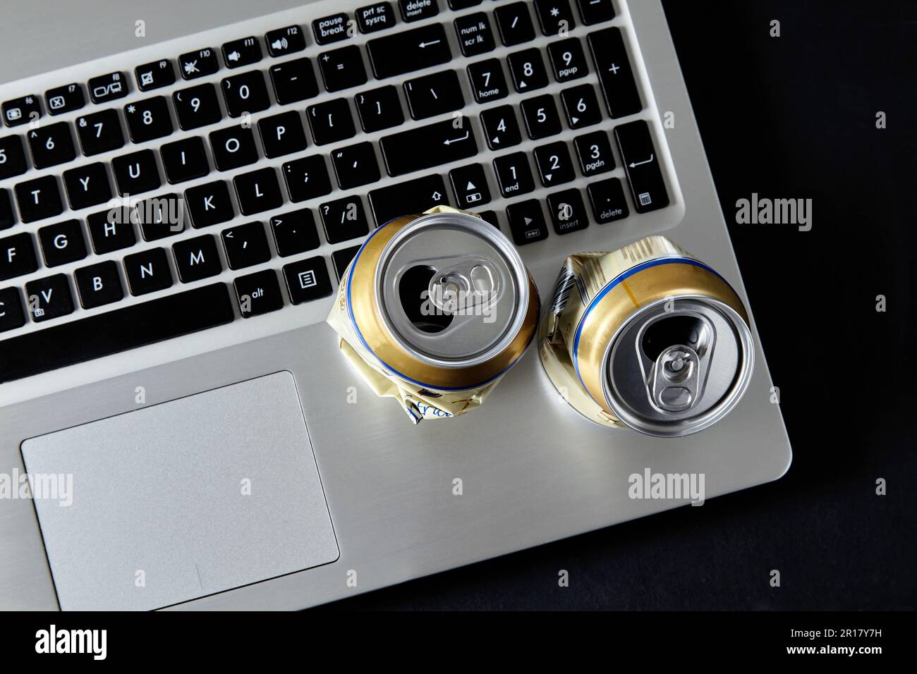 Empty crushed cans of beer on a laptop keyboard on a black background ...