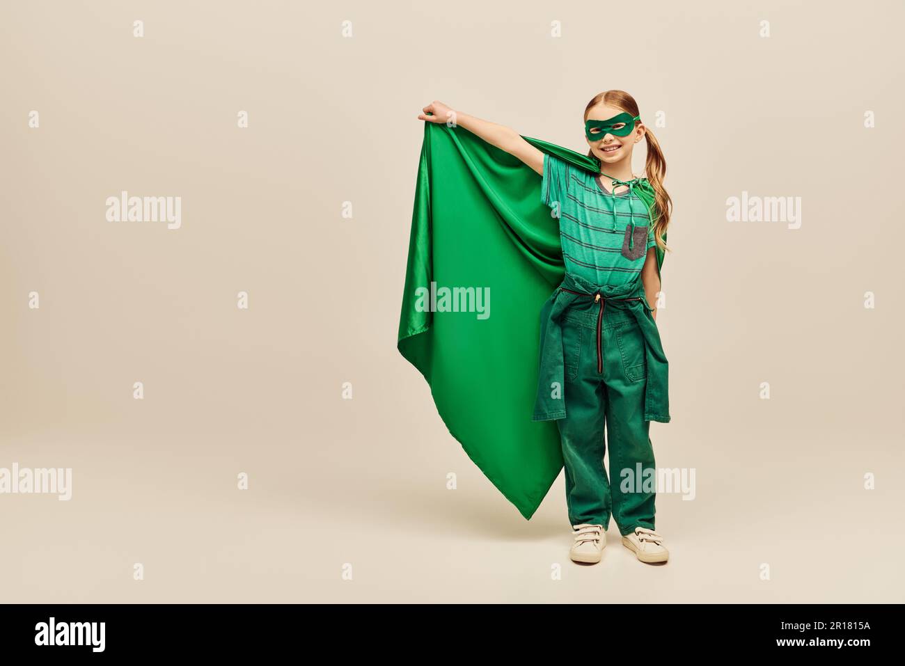 happy kid in superhero costume and mask on face holding green cloak ...