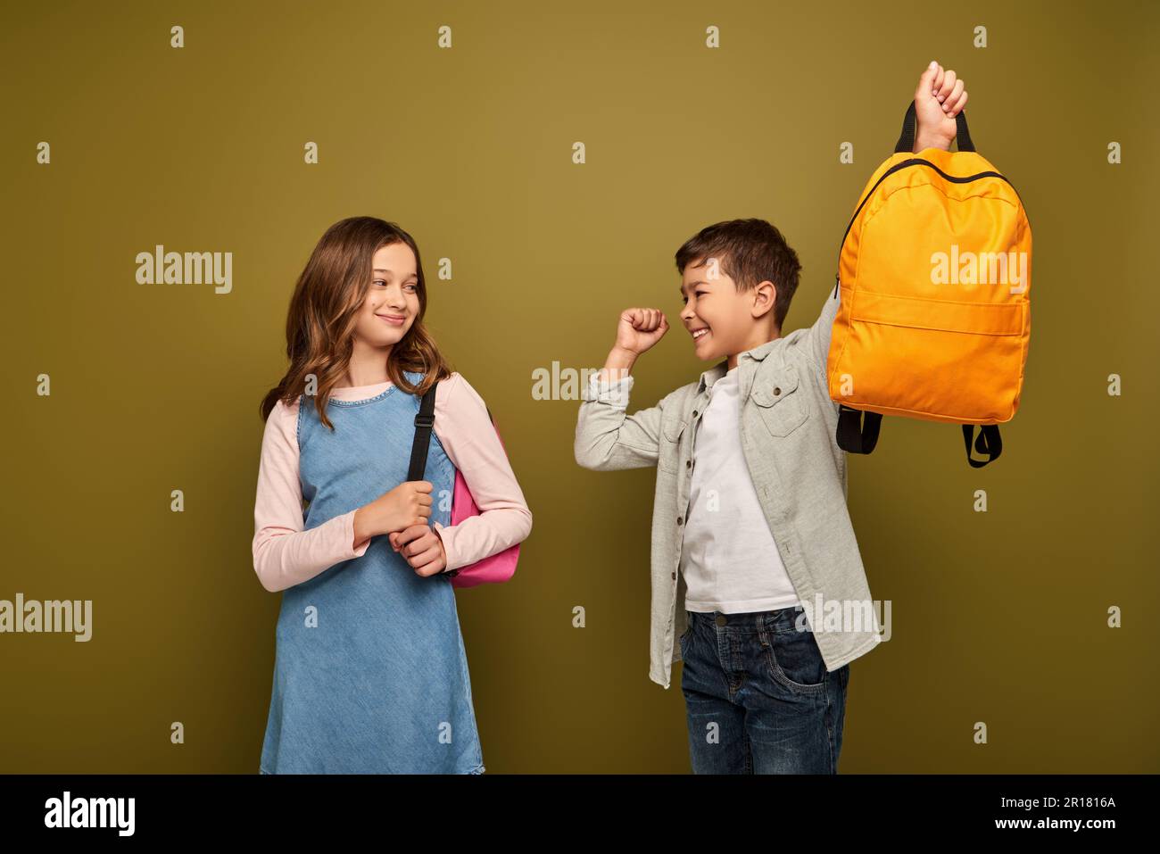 Excited multiracial boy holding backpack and showing yes gesture near ...