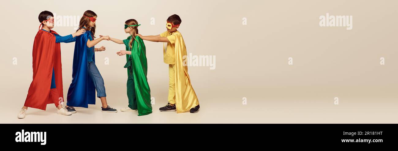 side view of multicultural kids in colorful superhero costumes with ...