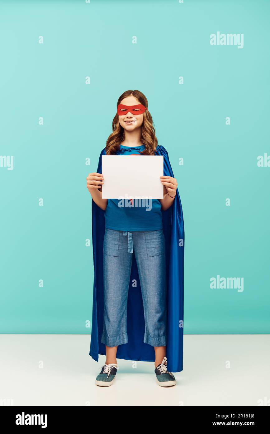 positive preteen girl in superhero costume with cloak and red mask ...