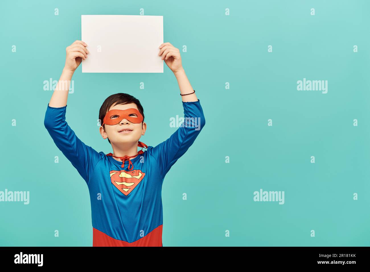 preteen asian boy in superhero costume with mask holding blank paper ...