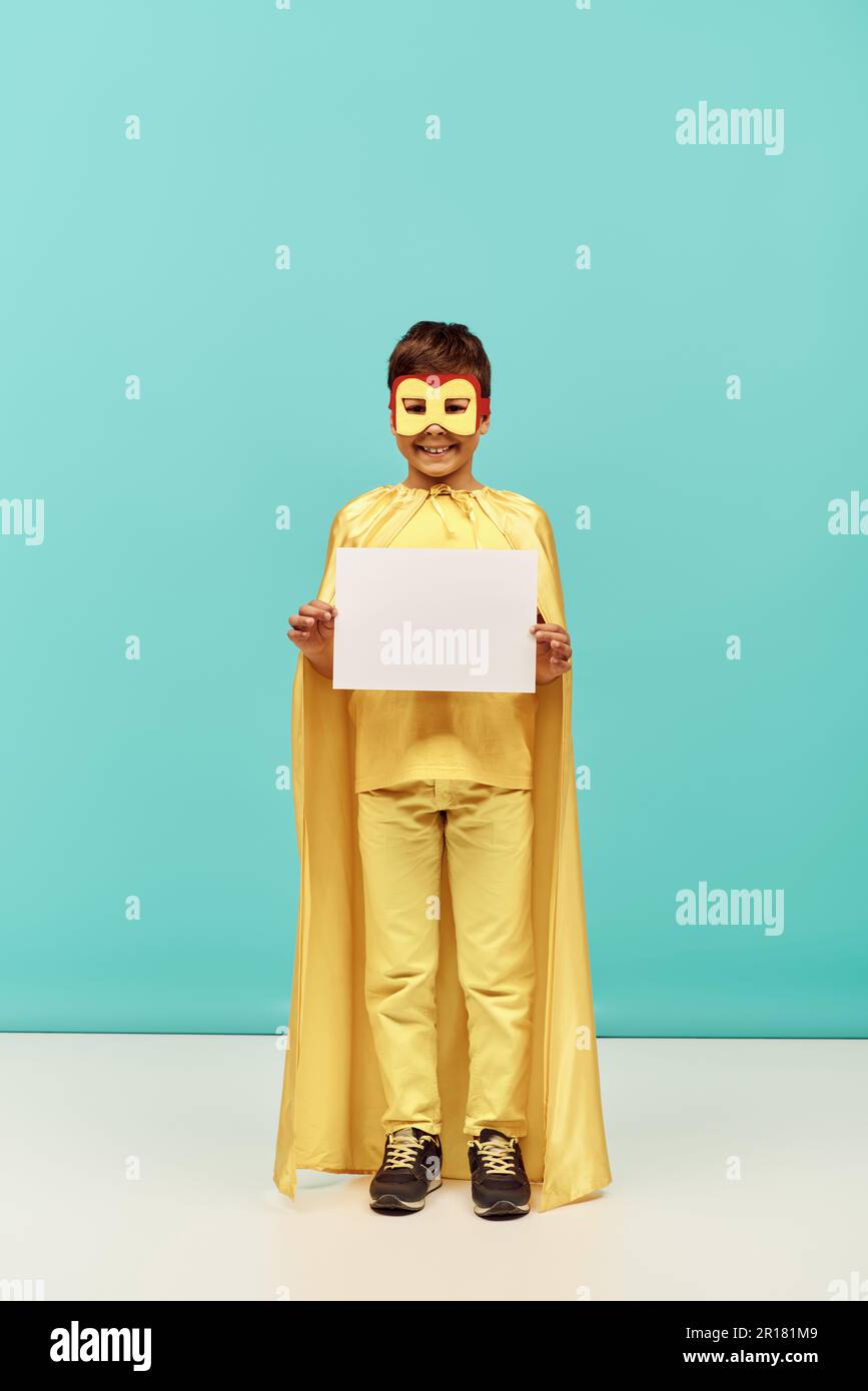 full length of positive multiracial boy in yellow superhero costume ...