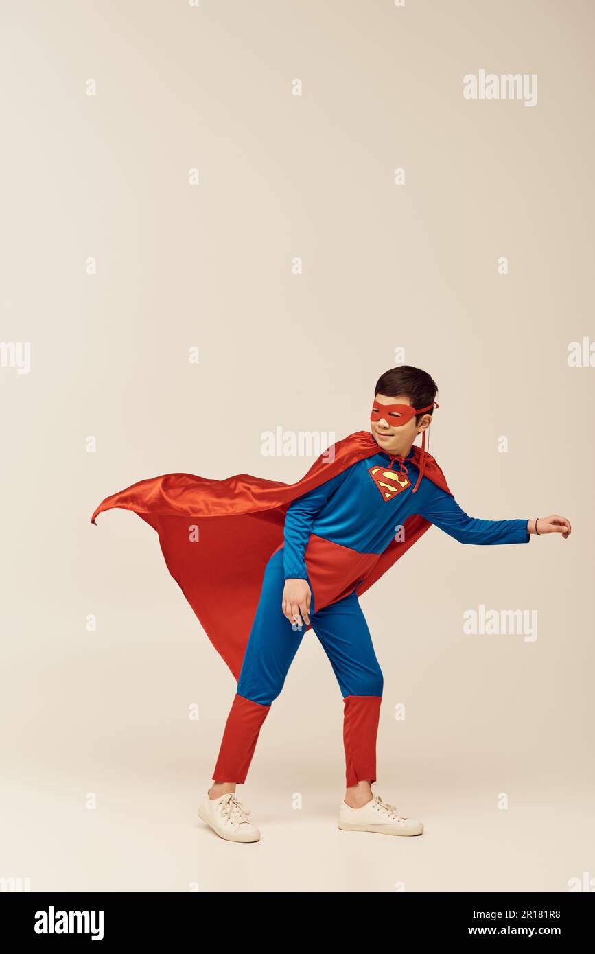 full length of happy asian boy in superhero costume with cloak and mask ...