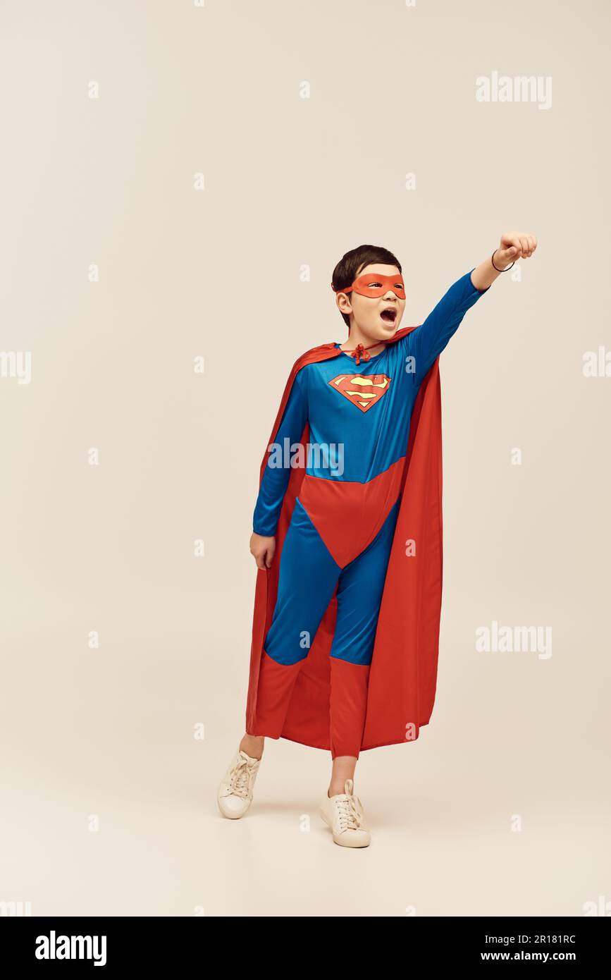 asian boy in superhero costume with cloak and mask on face screaming ...