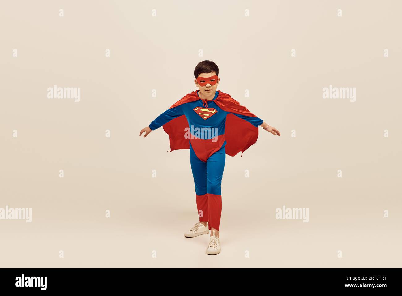 courageous asian boy in red and blue superhero costume with cloak and ...