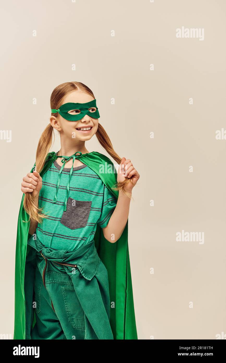 happy girl in green superhero costume with cloak and mask on face, with ...