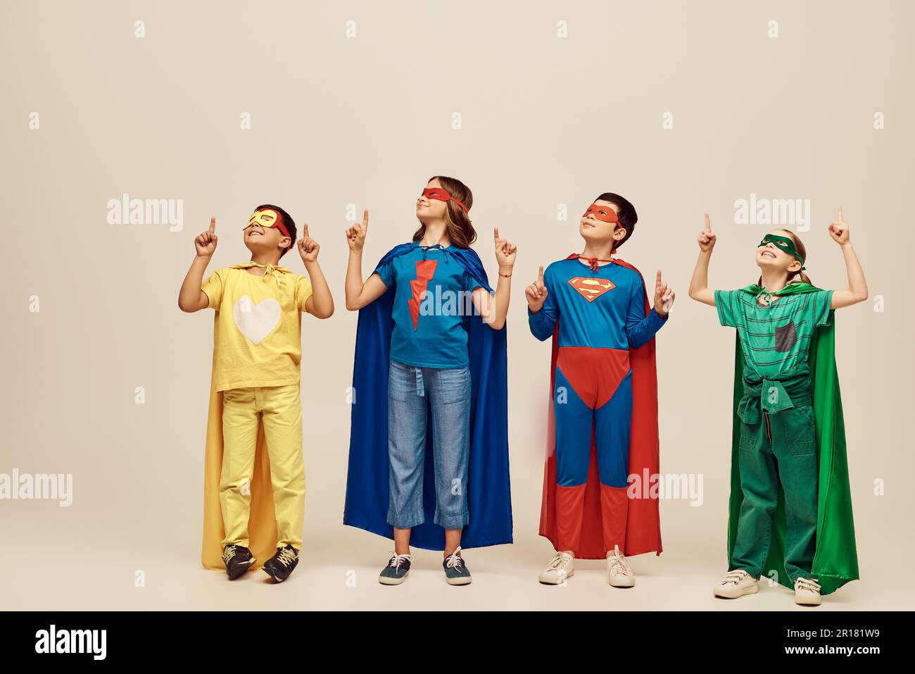 positive multicultural kids in colorful superhero costumes with cloaks ...