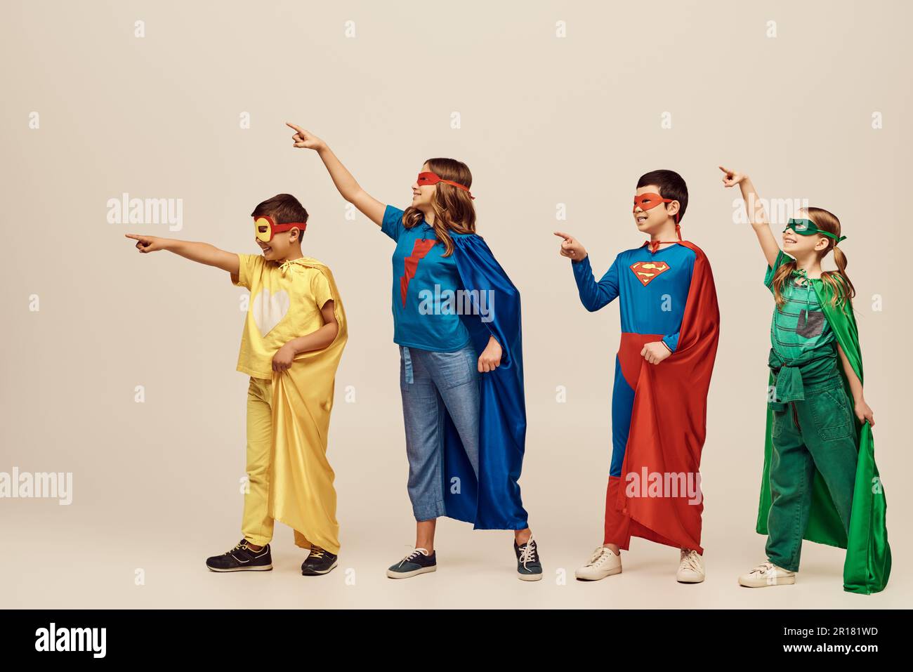 positive multicultural kids in colorful superhero costumes with cloaks ...