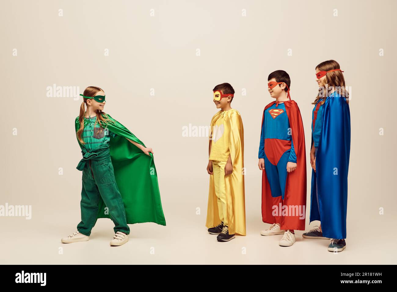 happy interracial preteen kids in colorful superhero costumes looking ...