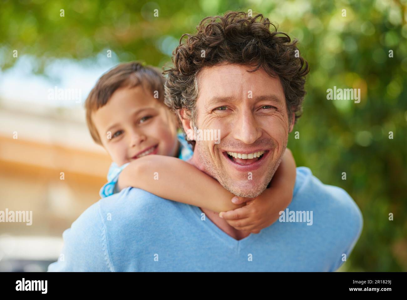 Hanging out with dad. Portrait of a father giving his son a piggyback ...