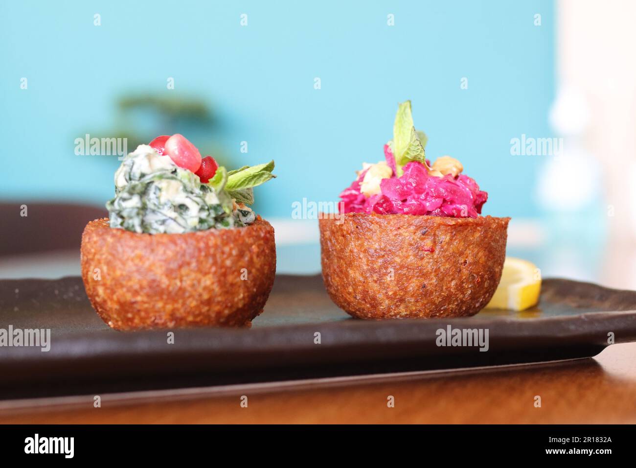 A black plate filled with falafel on a restaurant table Stock Photo - Alamy
