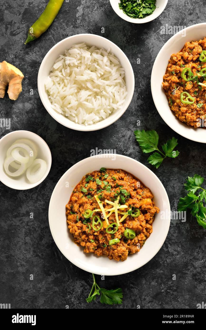 Bowls of keema curry and rice over dark stone background. Indian and ...