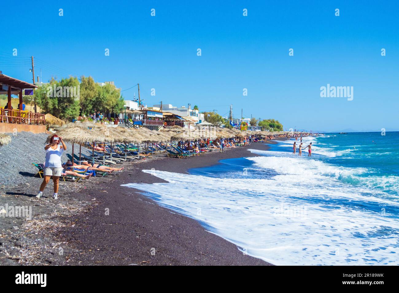Alleys,loungers and reed umbrellas at the Black Beach of Kamari village ...
