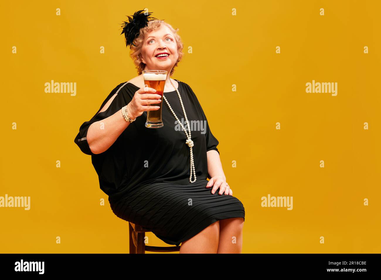 Portrait happy middle-aged woman wearing black dress holding lager beer ...