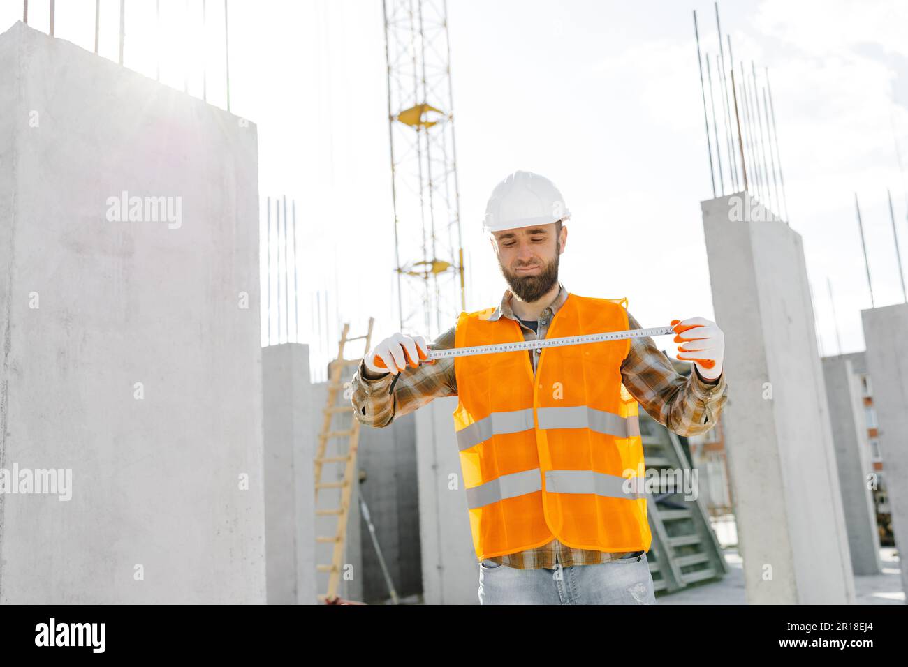 Builder repairman, foreman in protective helmet and vest stands at ...