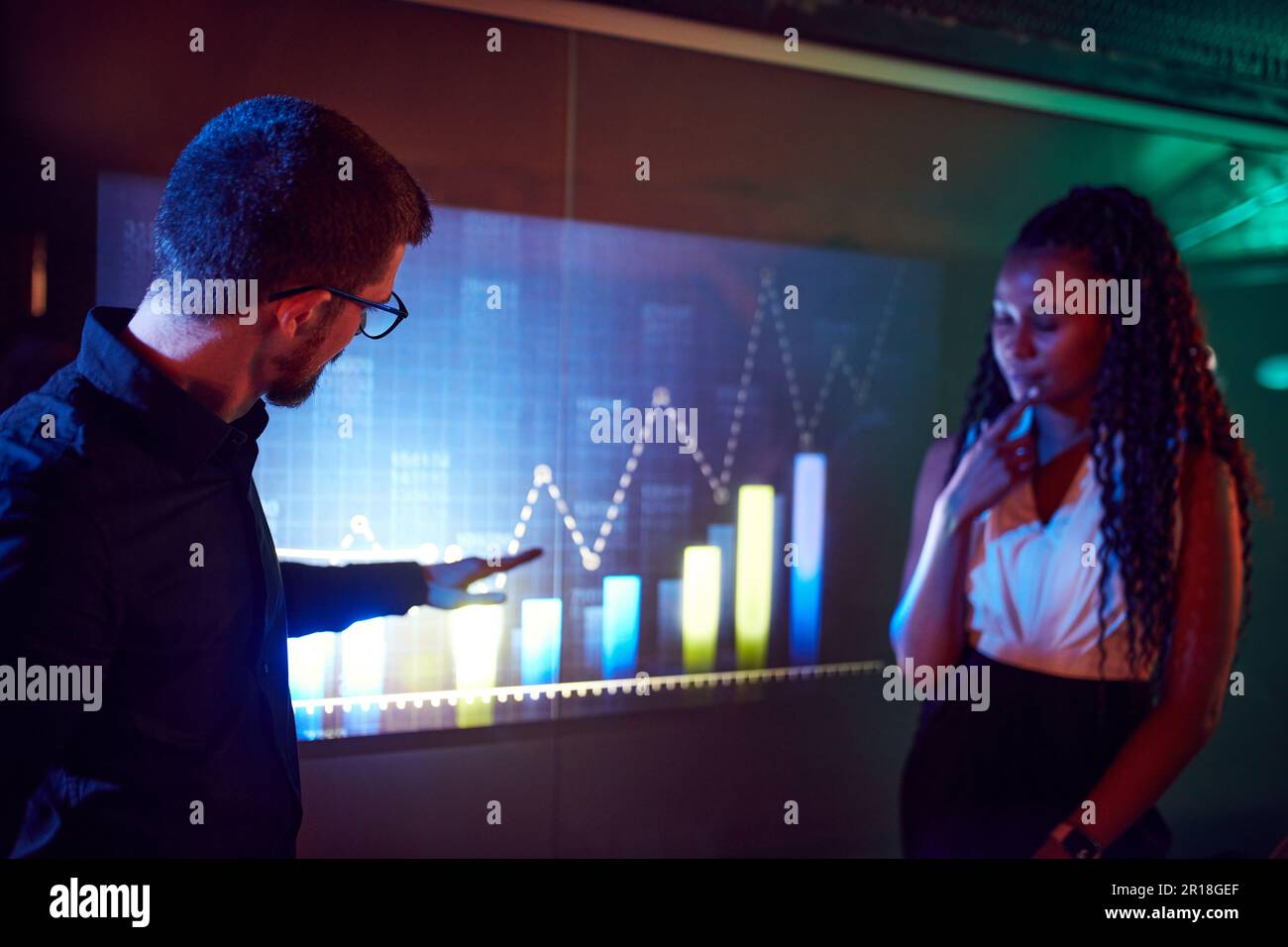 Man and woman, project leaders showing presentation on digital screen, graphs and analytics ...