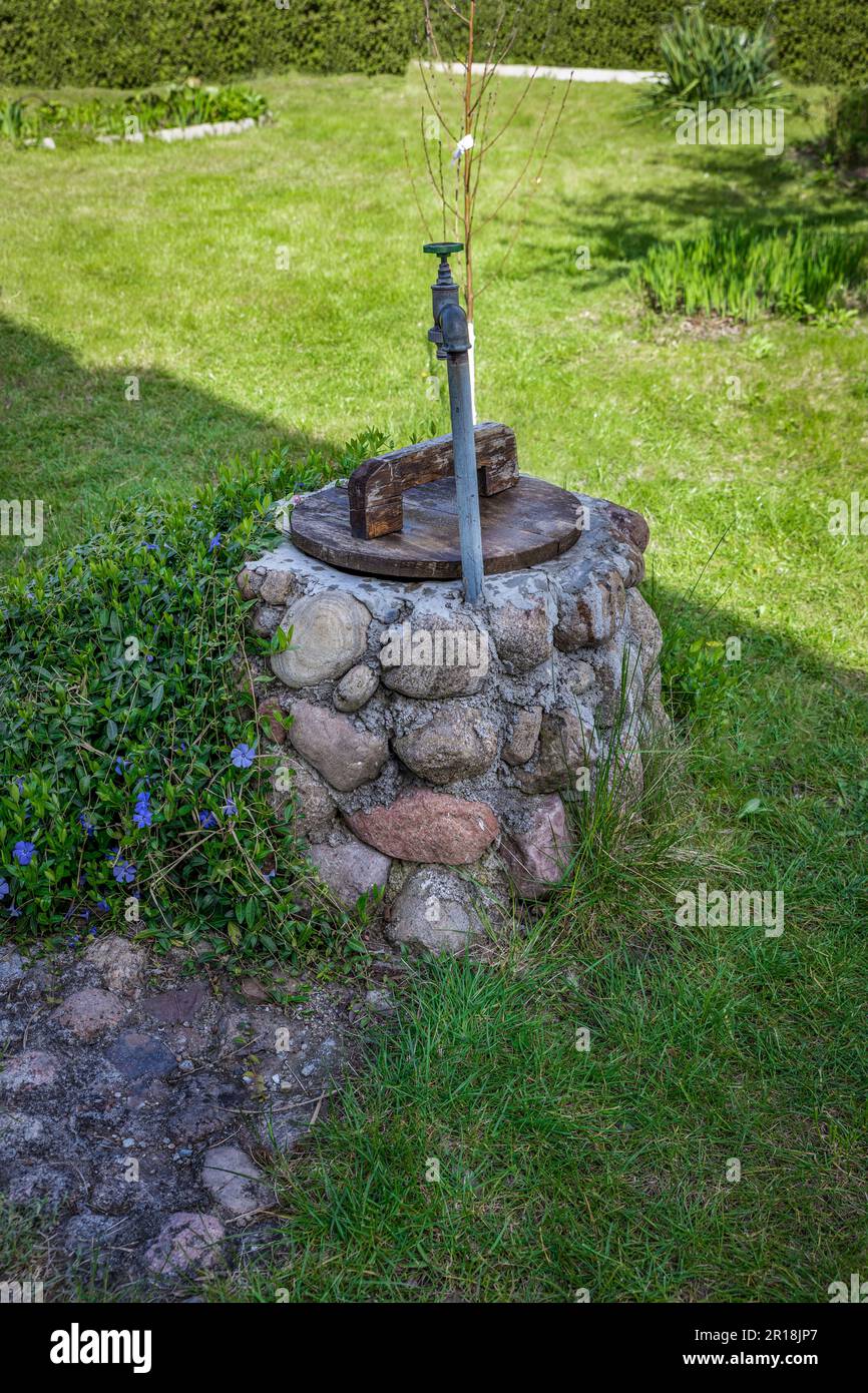 Stone well in a garden surrounded by lush greenery. Wells have been ...