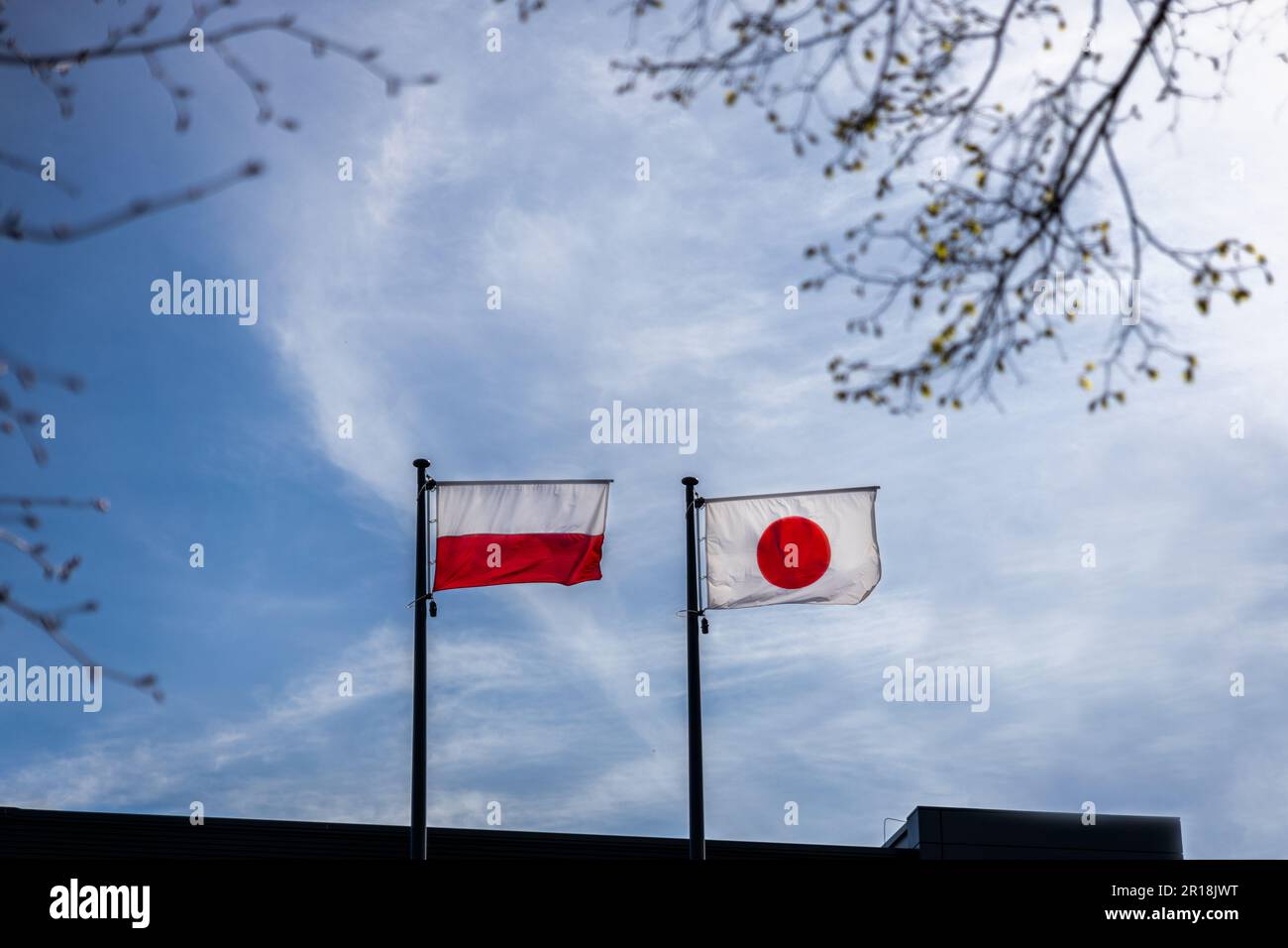 The flags of Poland and Japan on a banner against a blue sky. The red ...