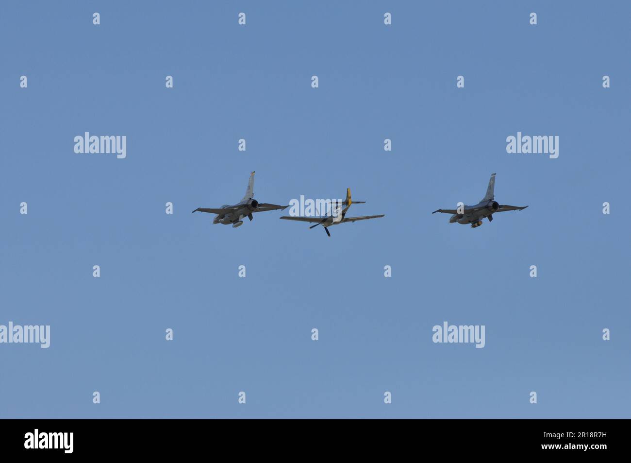 Two fighter jets flying with world war II propeller plane in formation ...