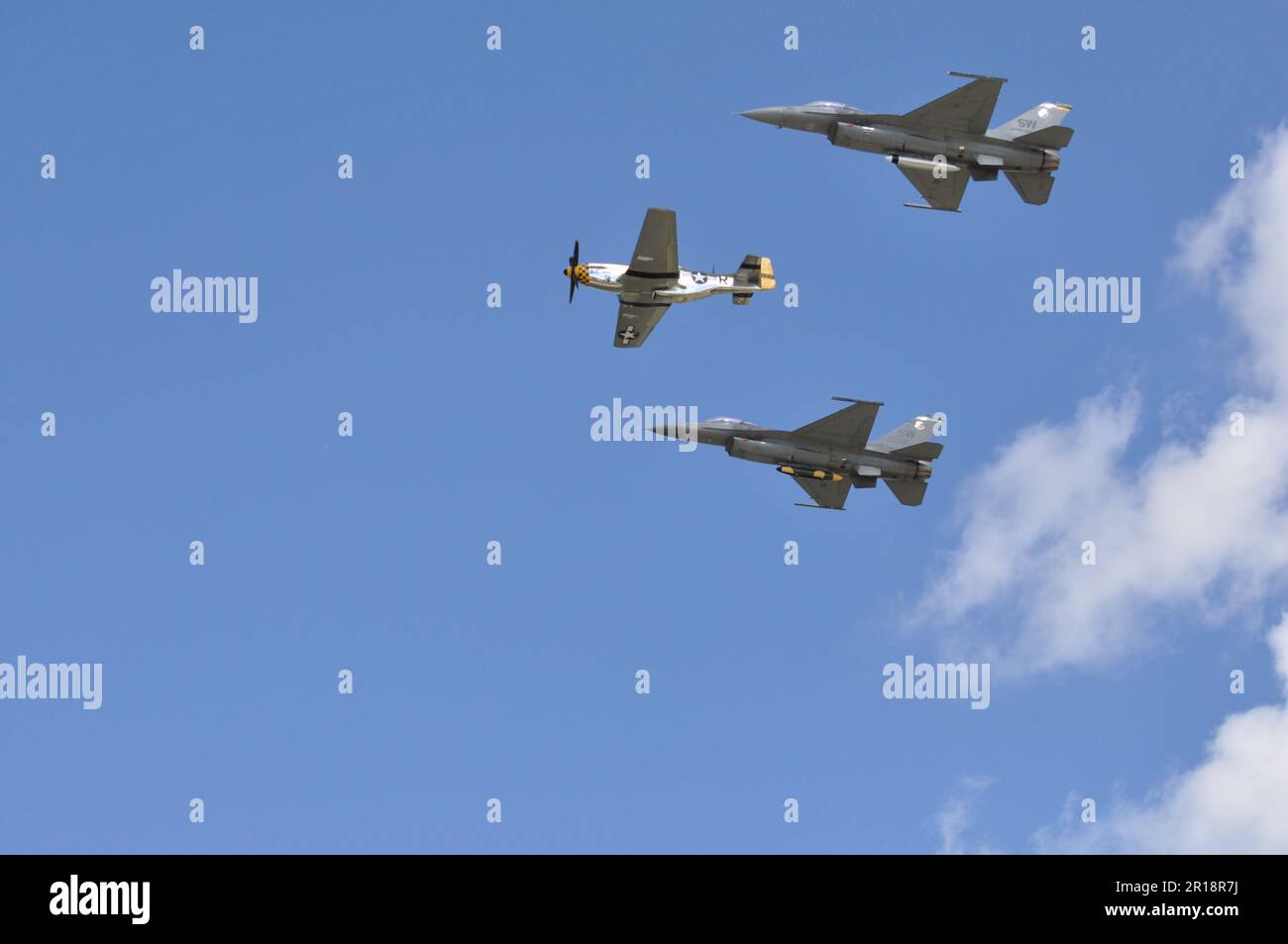 Two fighter jets flying with world war II propeller plane in formation ...