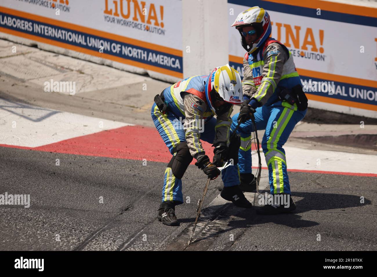 Two people dressed in motor racing attire making repairs on a race ...