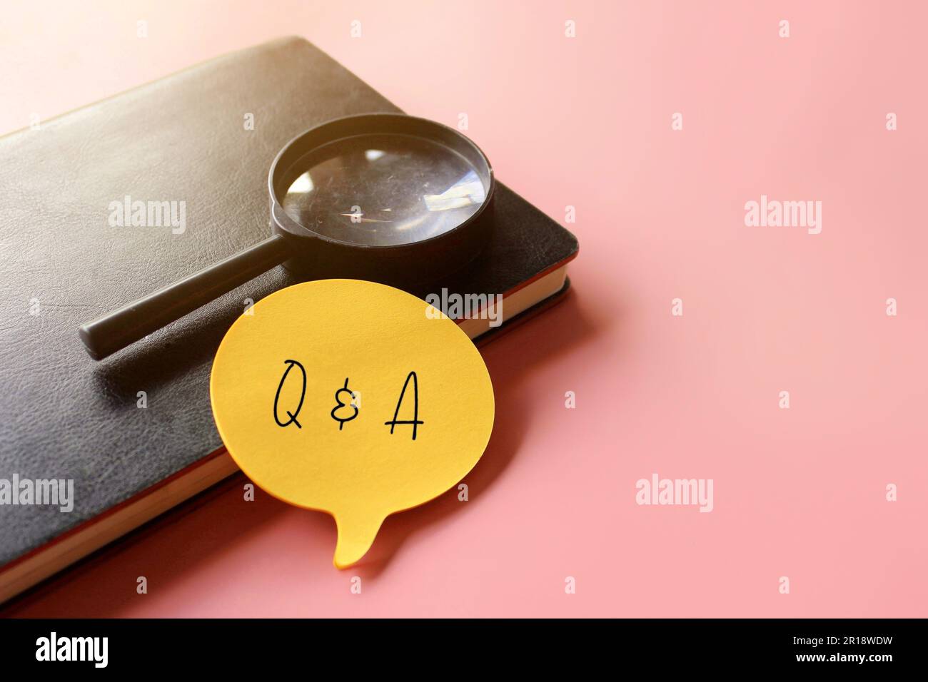 Close up image of book, magnifying glass and speech bubble with text Q ...