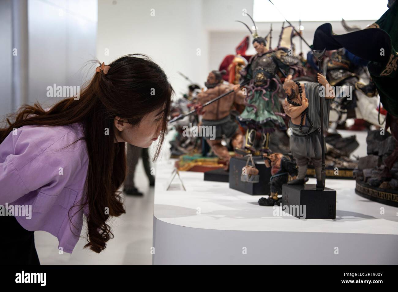 Visitors observe a collection of superhero statues at Statue4Heroes ...