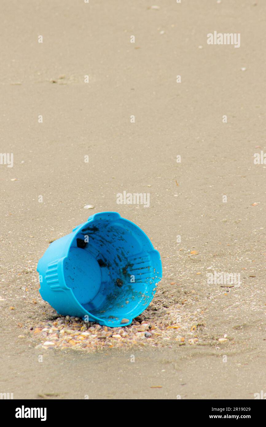 empty lone bucket left unattended on sand at the beach, pollution ...