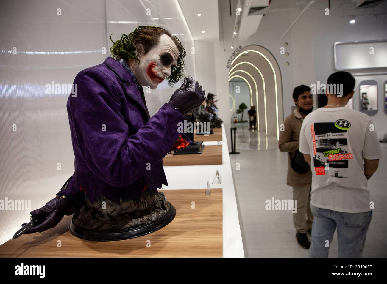 Visitors observe a collection of superhero statues at Statue4Heroes ...