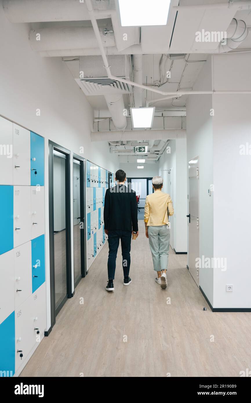 Colleagues walking along storage cells to office Stock Photo - Alamy