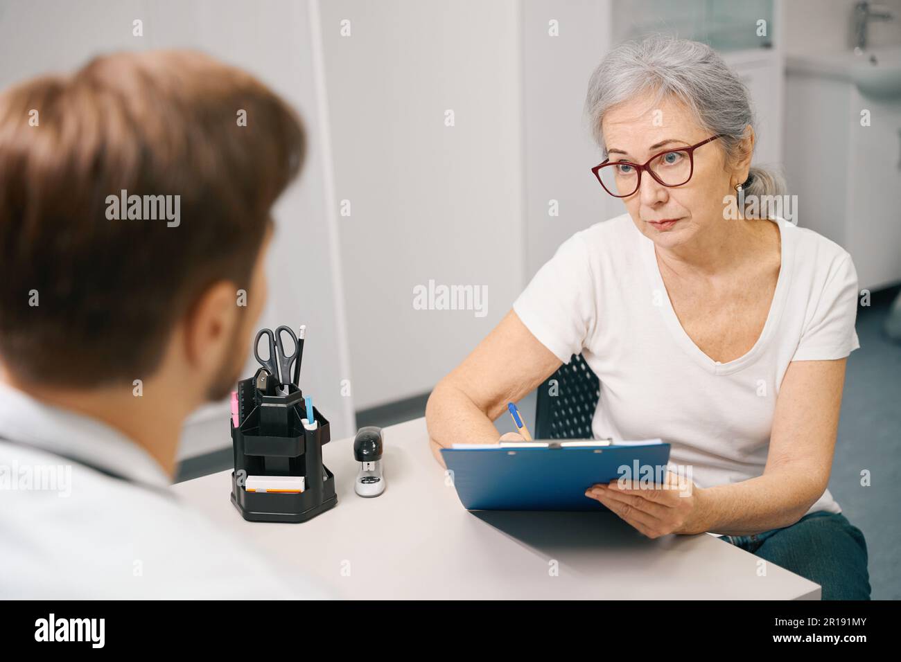 Elderly patient fills out a medical form at doctors appointment Stock ...