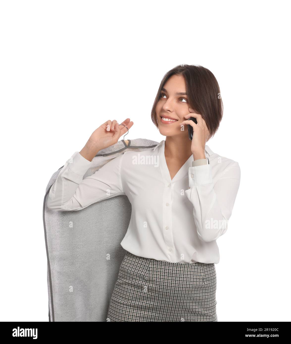 Woman holding garment cover with clothes while talking on phone ...