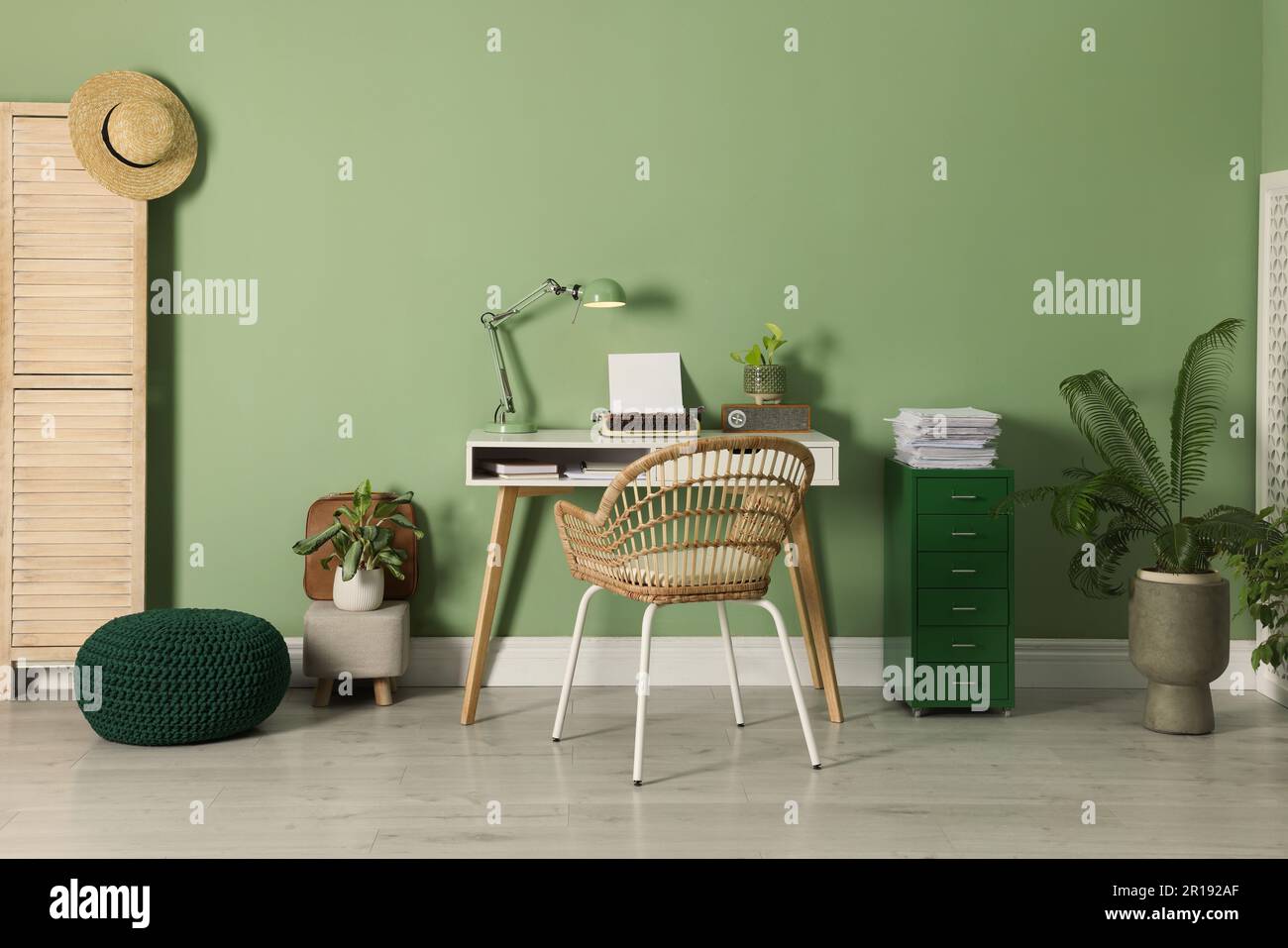 Writer's workplace with typewriter on wooden desk near pale green wall ...