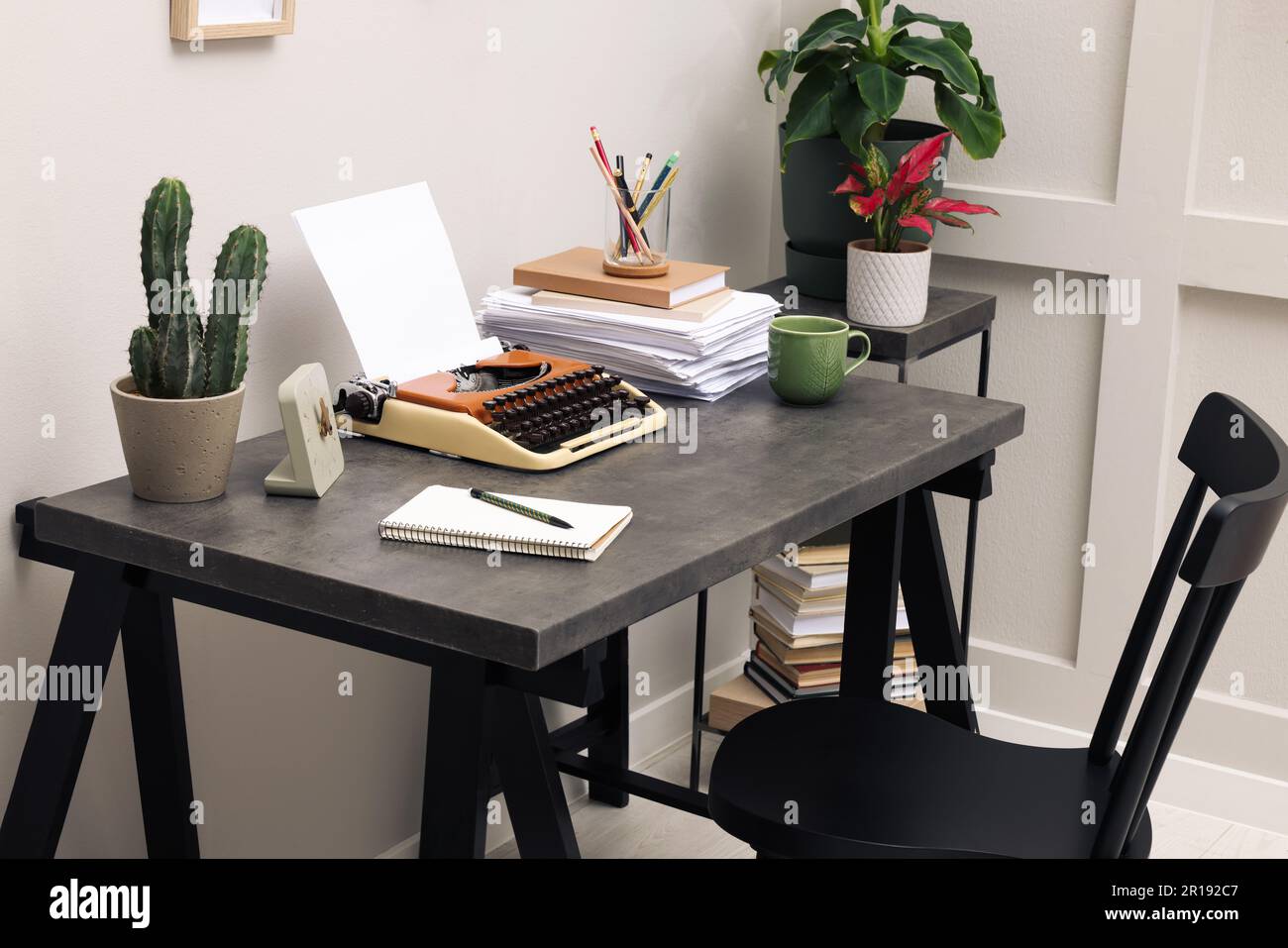 Typewriter and stack of papers on dark table in room. Writer's ...
