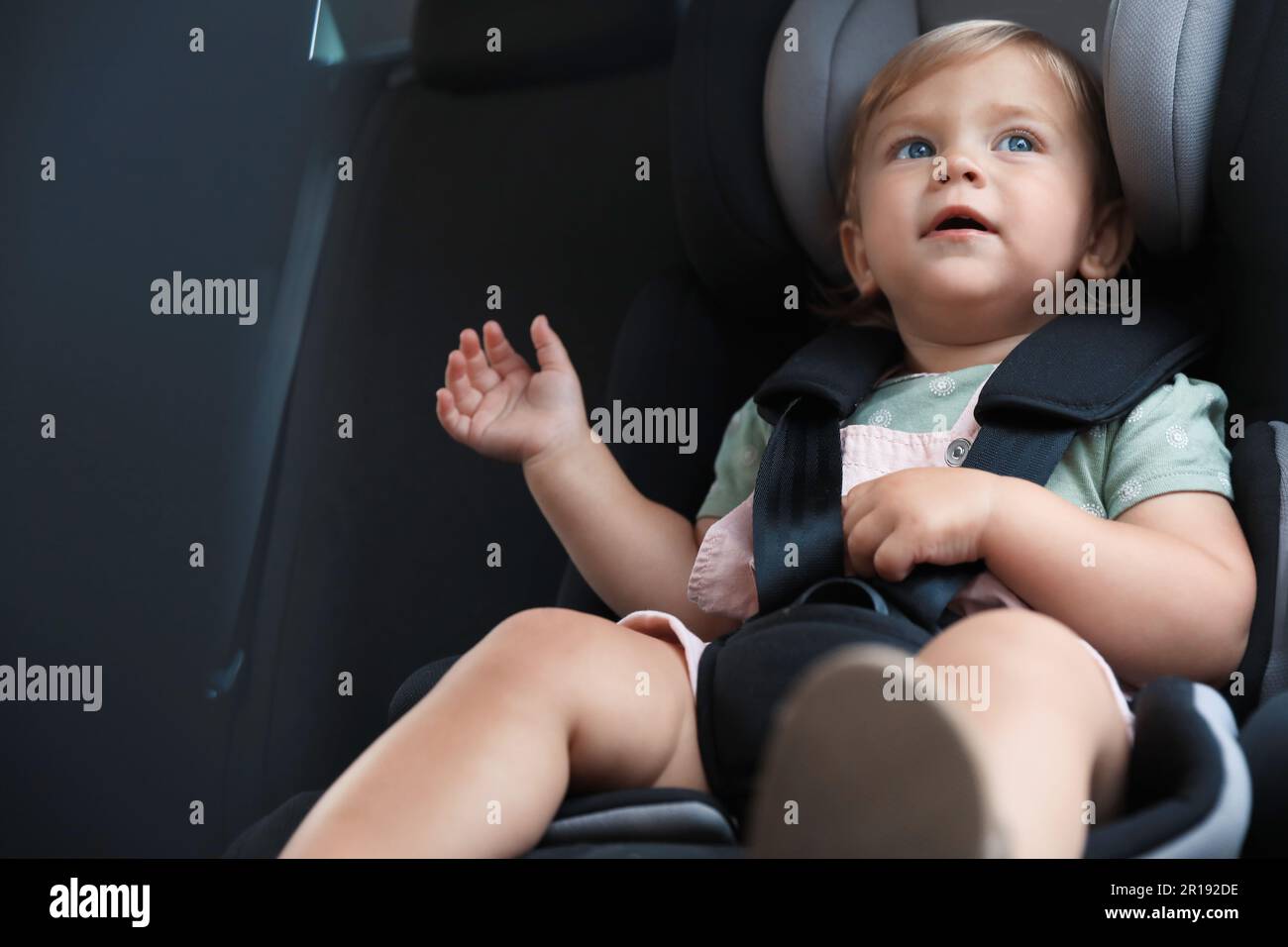 Cute little girl sitting in child safety seat inside car Stock Photo ...
