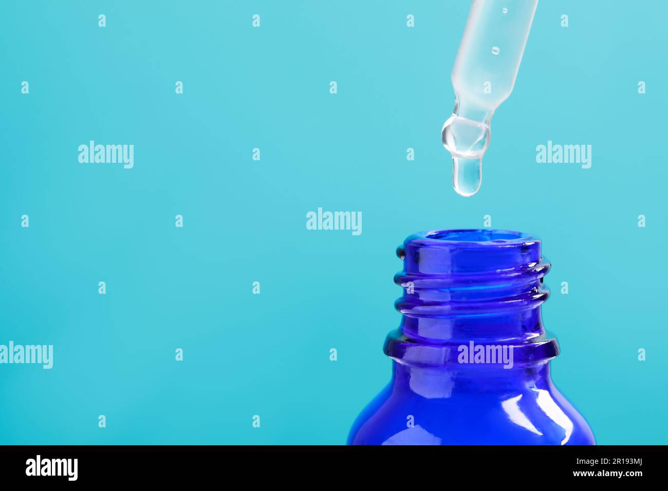 Dripping serum from pipette into bottle on light blue background ...