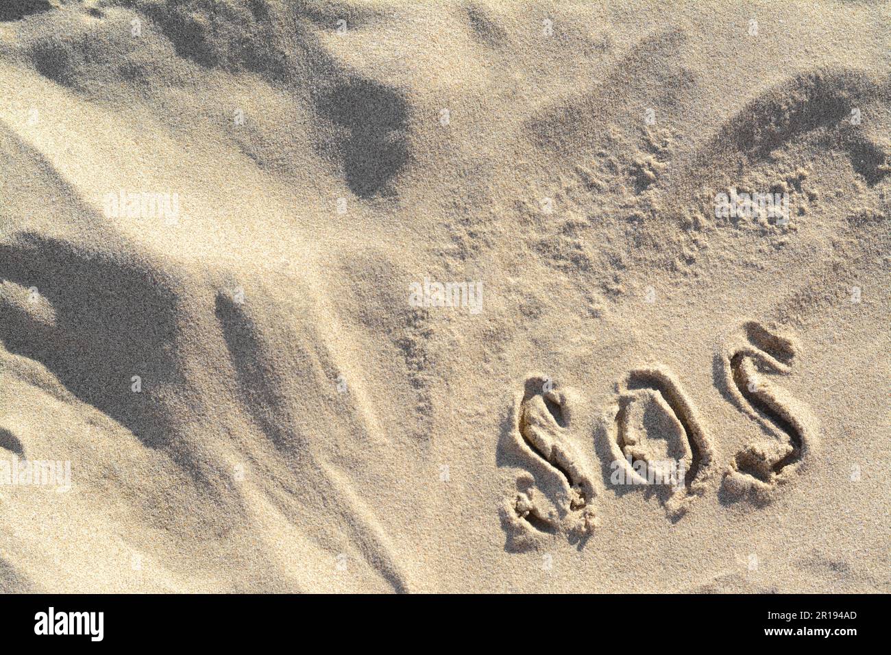 SOS message written on sandy beach outdoors, top view. Space for text ...