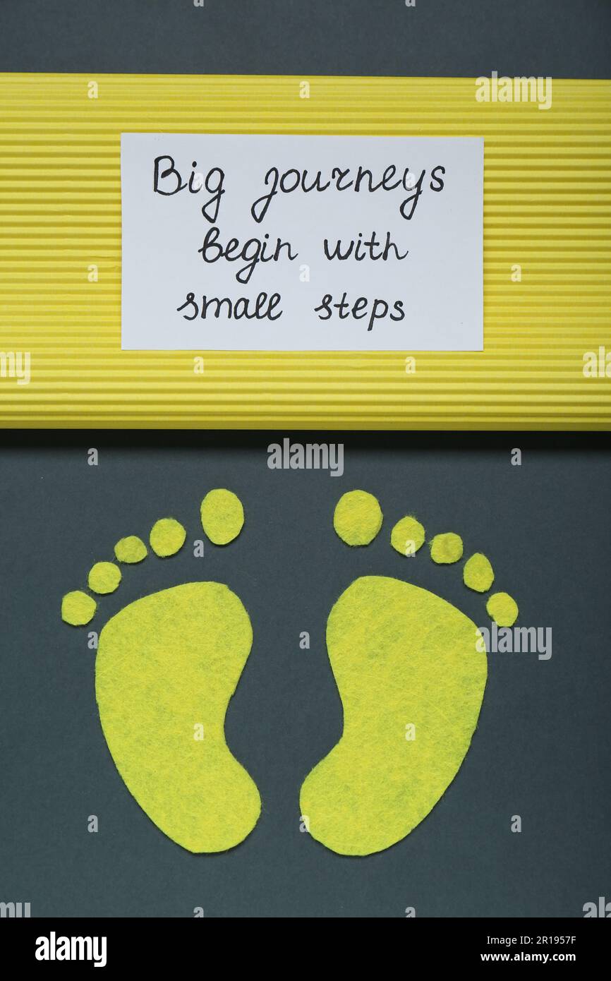 Card with phrase Big Journeys Begin With Small Steps and paper feet on ...