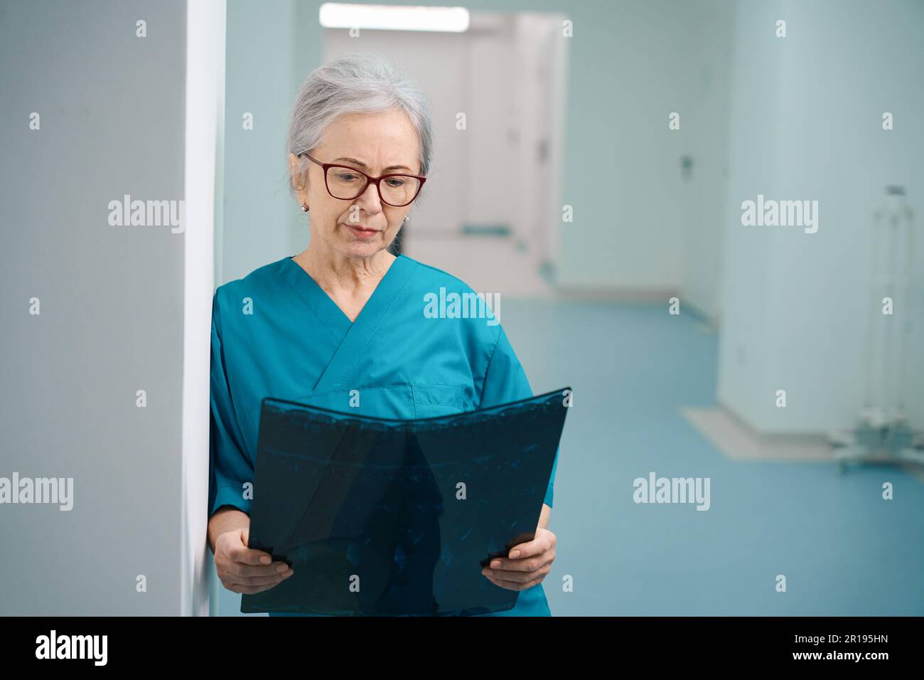 Elderly woman medic stands in hospital corridor with MRI scan Stock ...