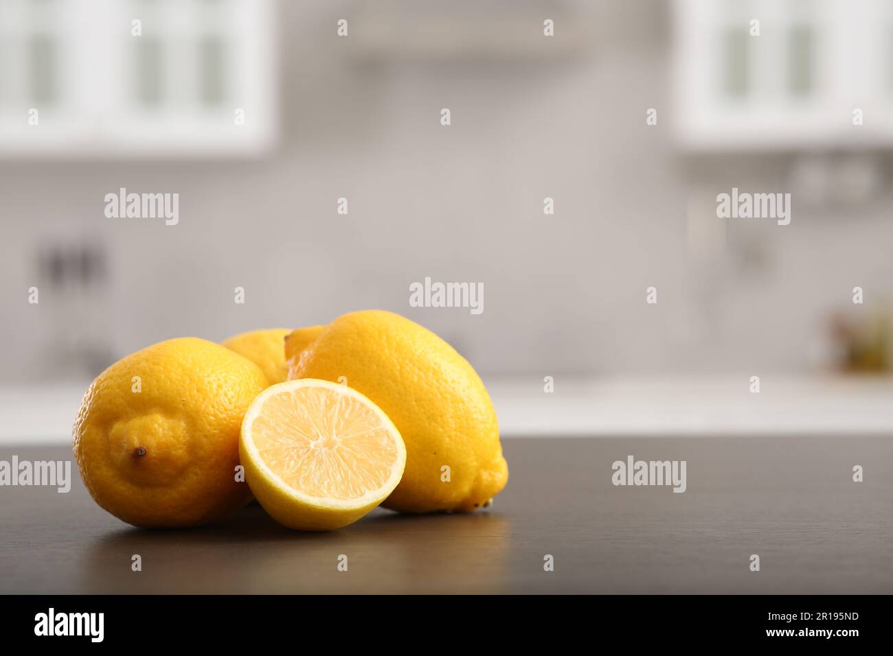 Whole and cut lemons on wooden counter in kitchen, space for text Stock ...