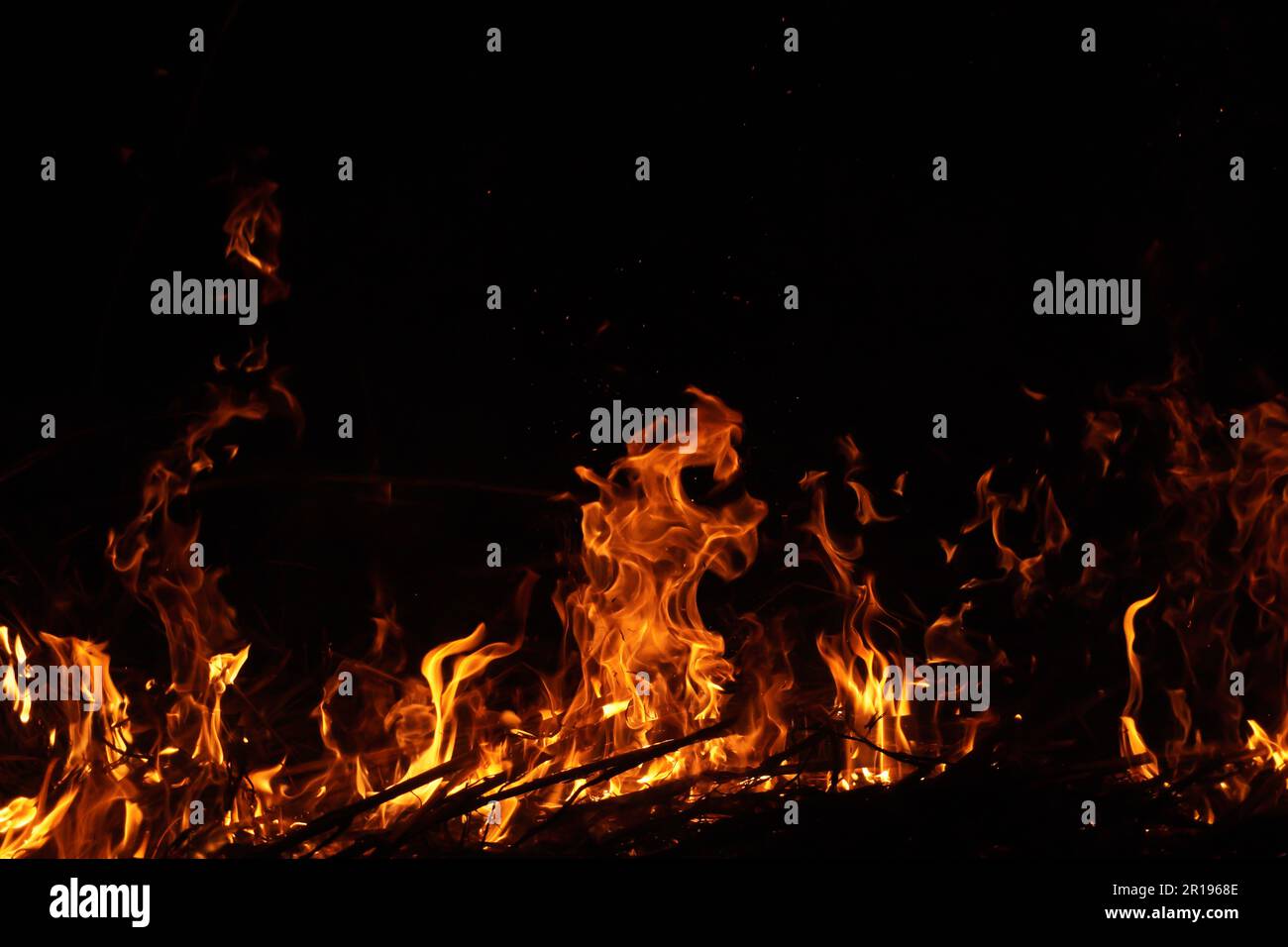 Burning red hot sparks fly from large fire in the night sky. Fire ...