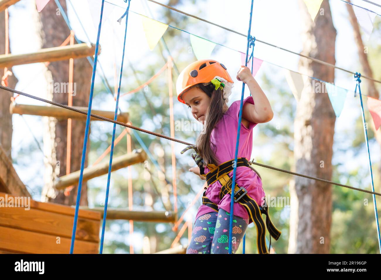 Happy school girl enjoying activity in a climbing adventure park on a ...